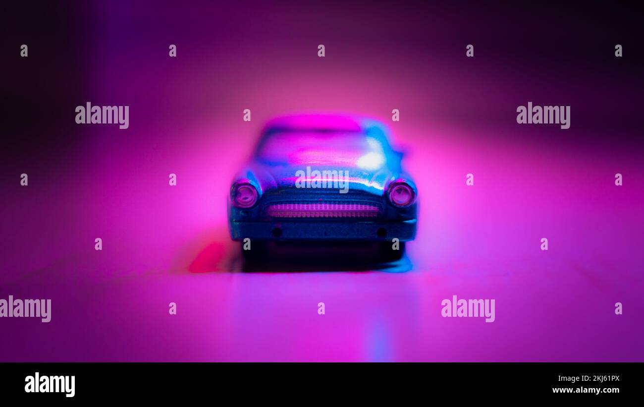 A blue classic retro toy car on the floor with the reflection of ...