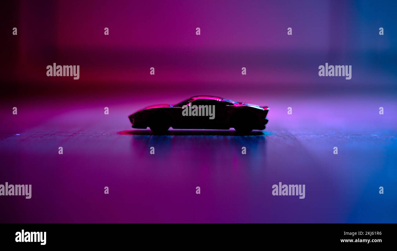 A classic retro toy car on the floor with the reflection of blueish ...