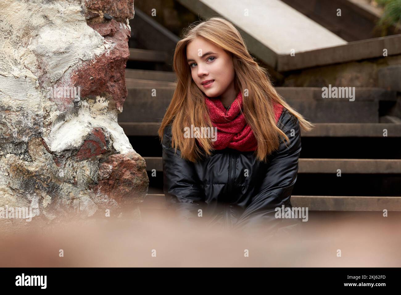 a young girl in a red skirt sits on the steps in the park in autumn ...