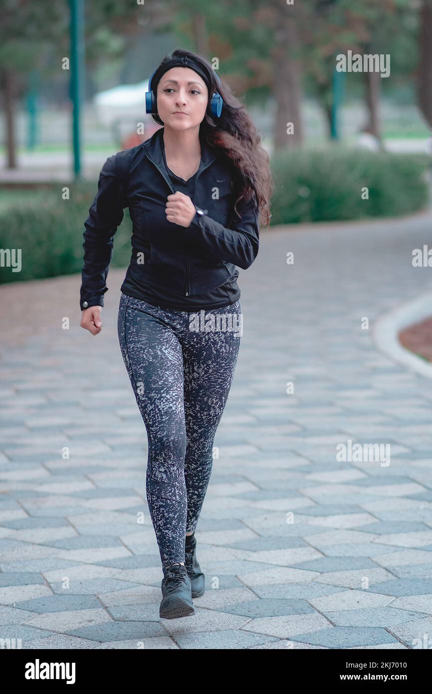 Woman running on the path of a park. Active sporty latina female ...