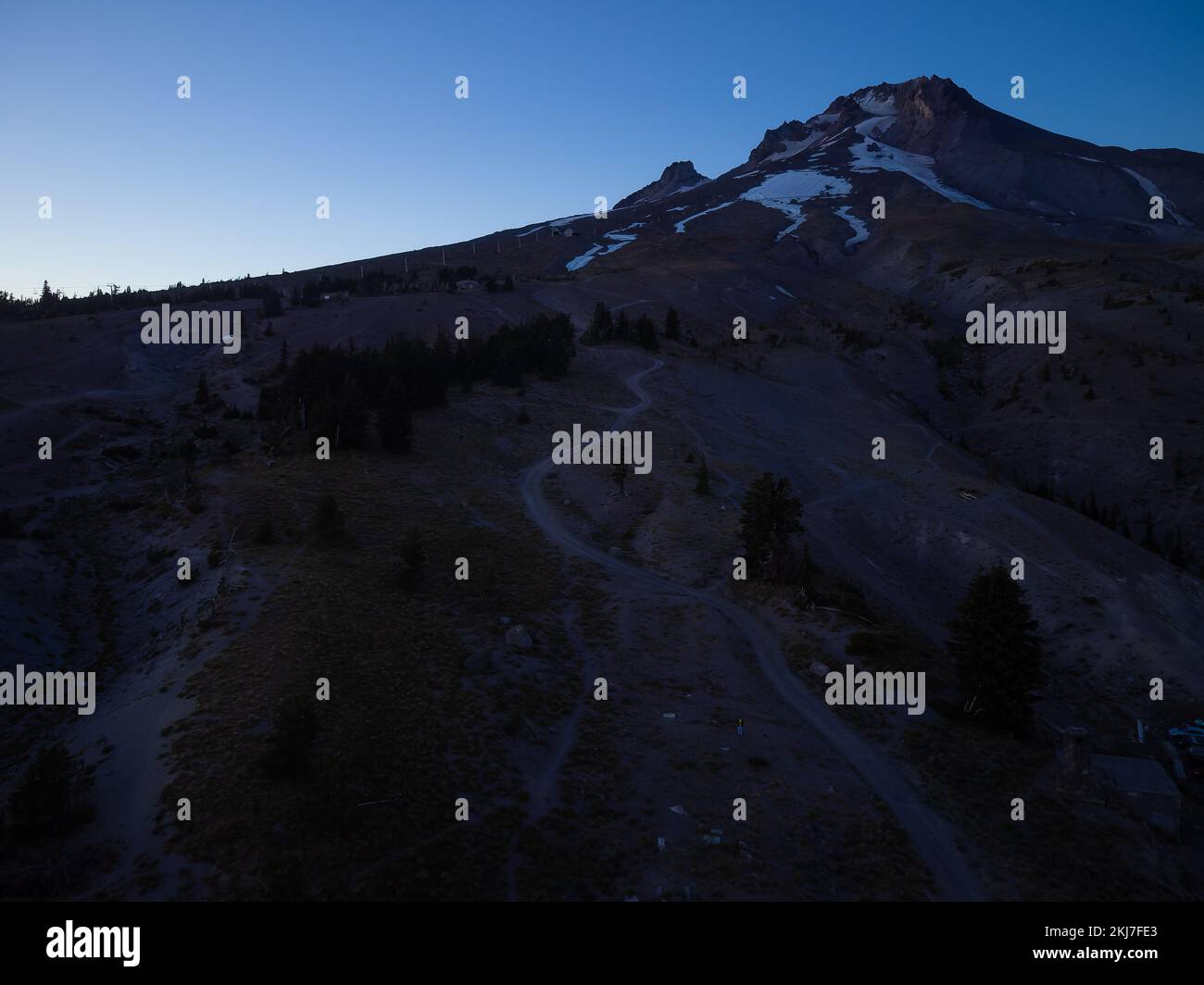 Twilight. Mountainous terrain, pine trees, hiking trails lead high into ...