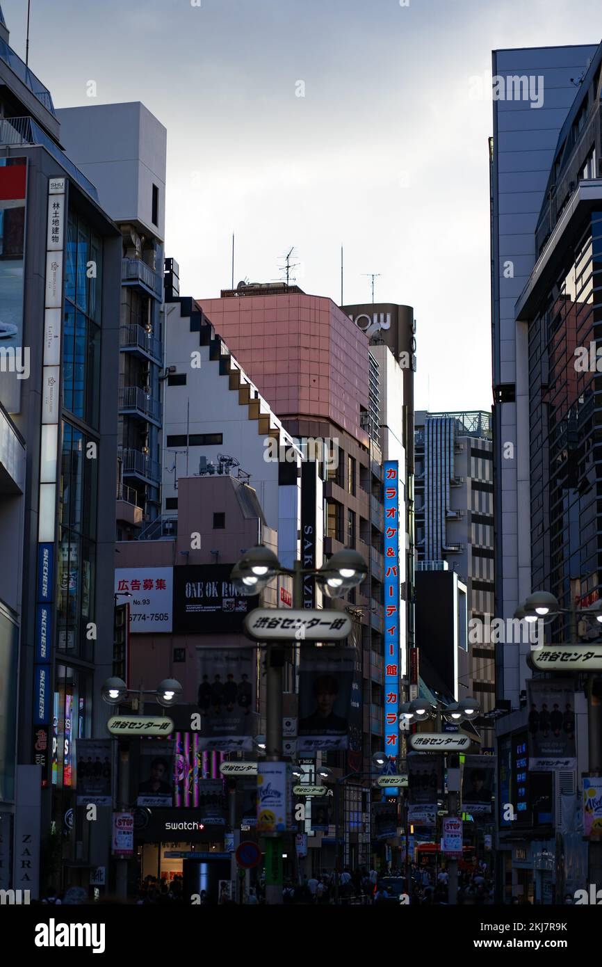 A crowded backstreet in Tokyo, Japan with tall buildings under a clear ...