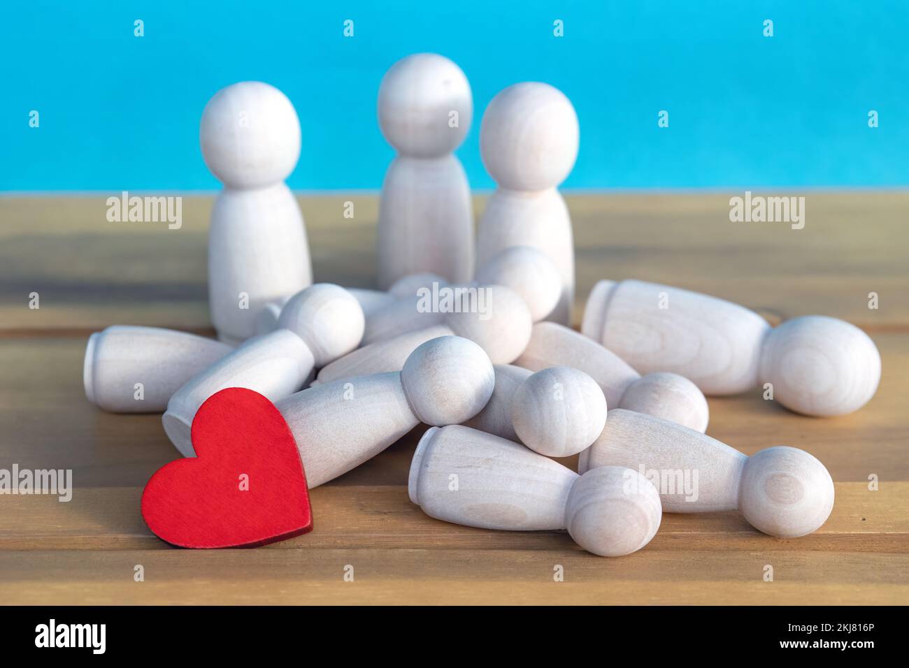 group of wooden figures and red heart, some lying down, some standing ...