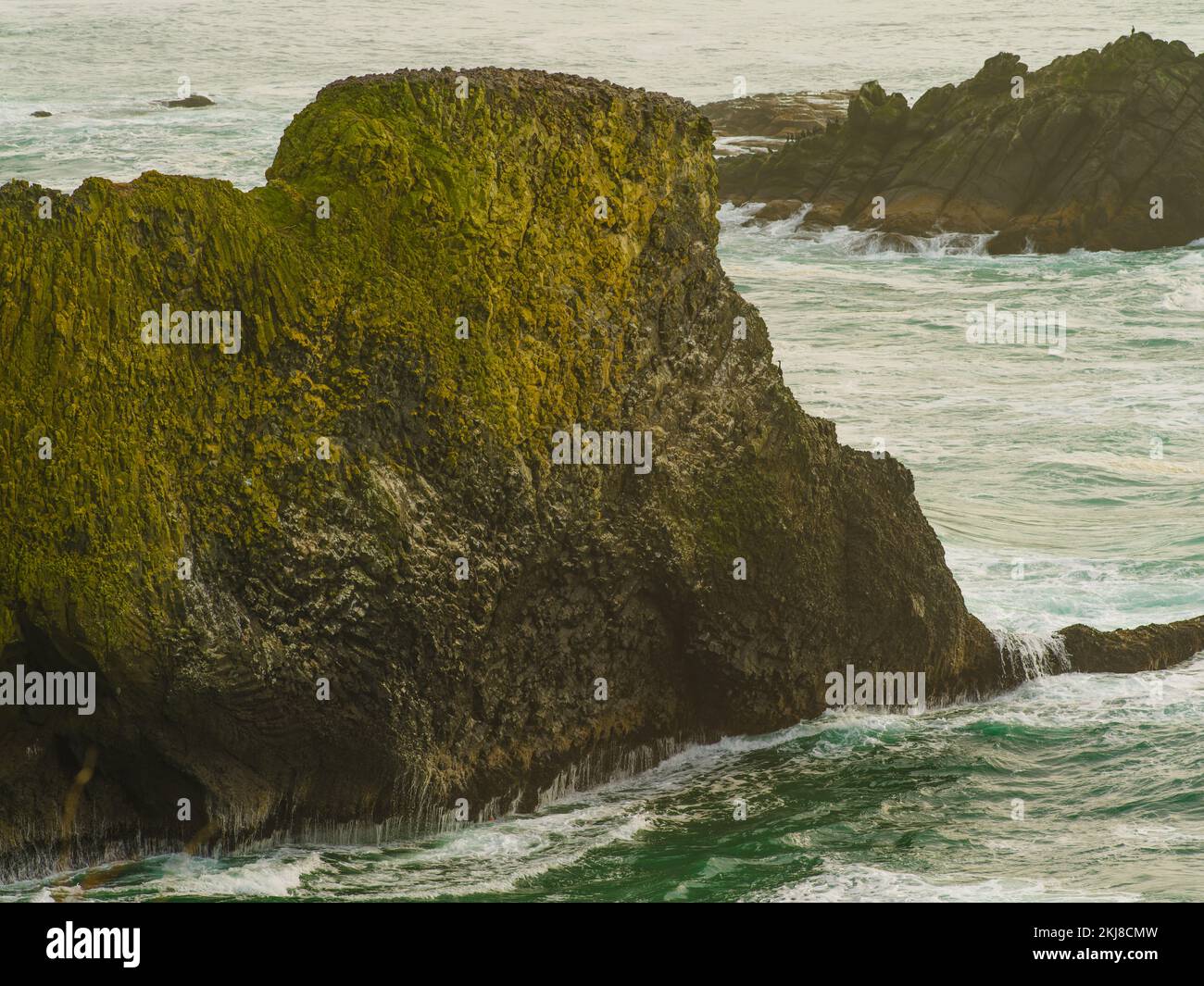 Rock covered with moss in the ocean. A large boulder can be seen in the ...
