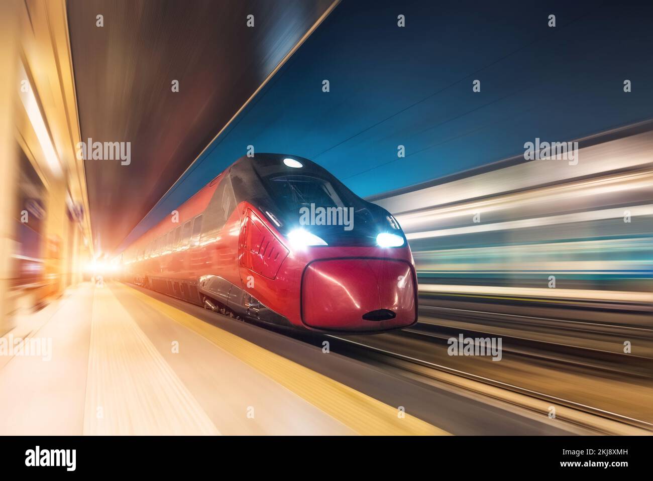 Night railway station, a passing train at speed. Modern travel ...