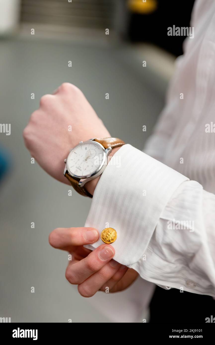 A vertical shot of a groom with an expensive watch buttons cuff link on ...