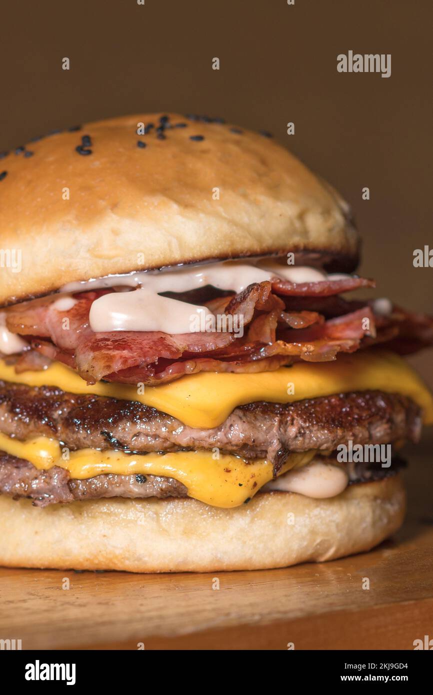 A vertical closeup of a cheeseburger on a wooden table Stock Photo - Alamy