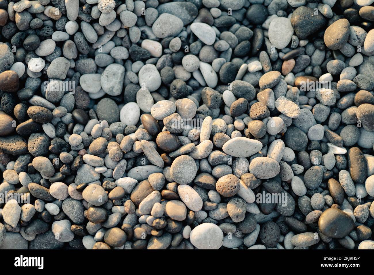 Multi-colored volcanic sea stones of different shapes backdrop from ...