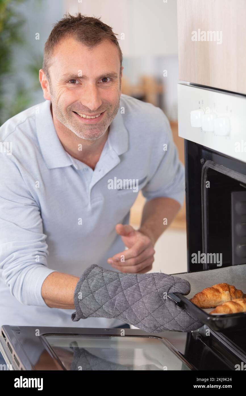 happy man baking croissants in oven indoors Stock Photo - Alamy