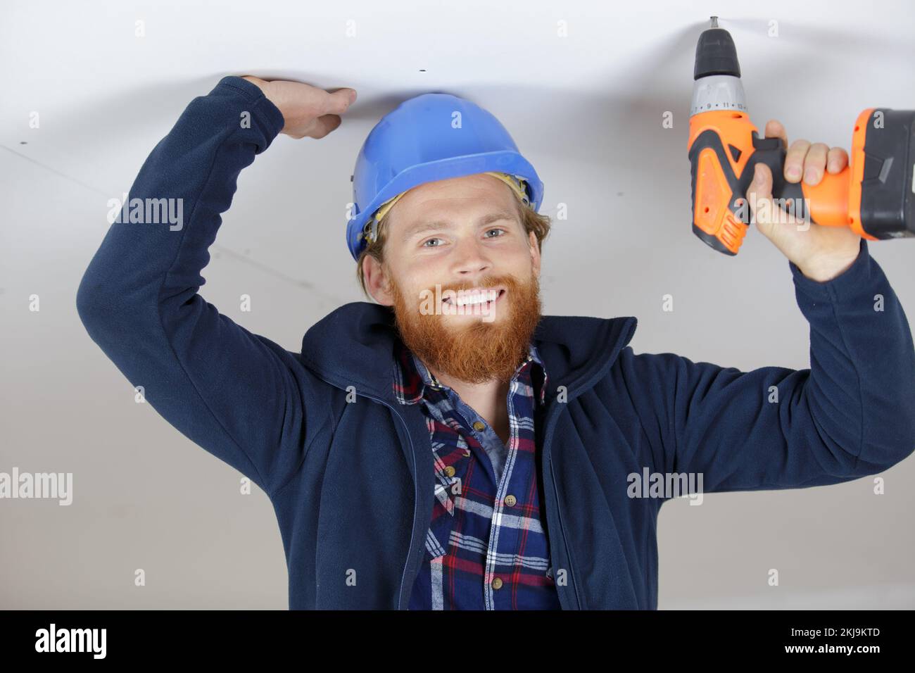 young man fixing ceiling using electrical screwdriver Stock Photo - Alamy