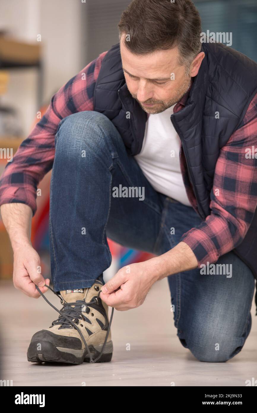 male worker doing shoes laces up Stock Photo - Alamy