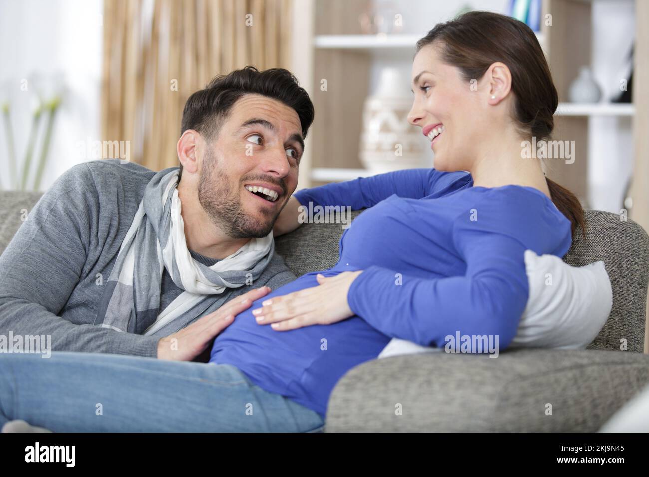 happy pregnant couple relaxing on couch at home Stock Photo - Alamy