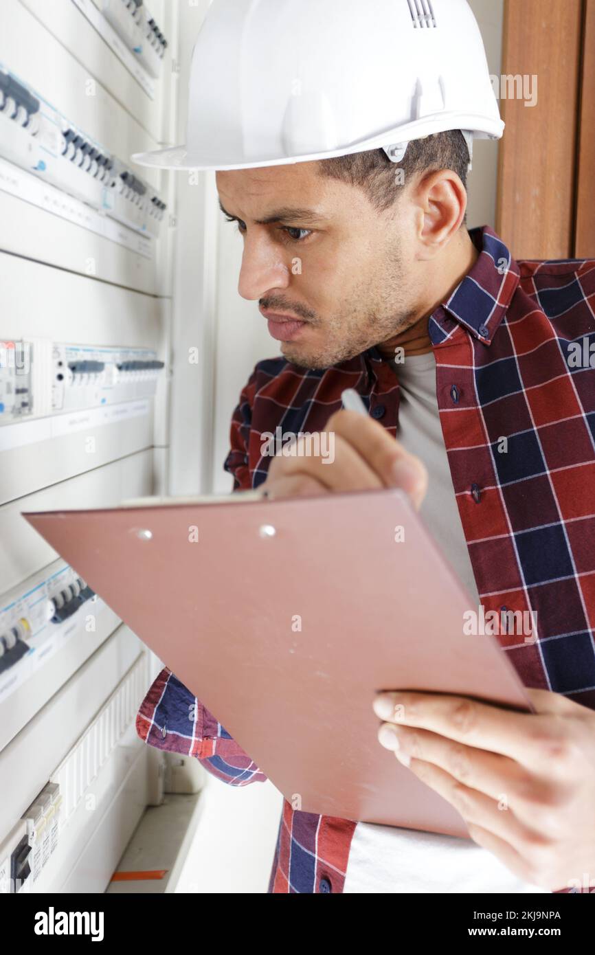 electrical engineer checking fusebox taking notes Stock Photo - Alamy