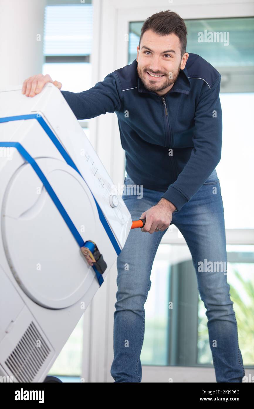 man moving a tumble drier on a trolley Stock Photo - Alamy