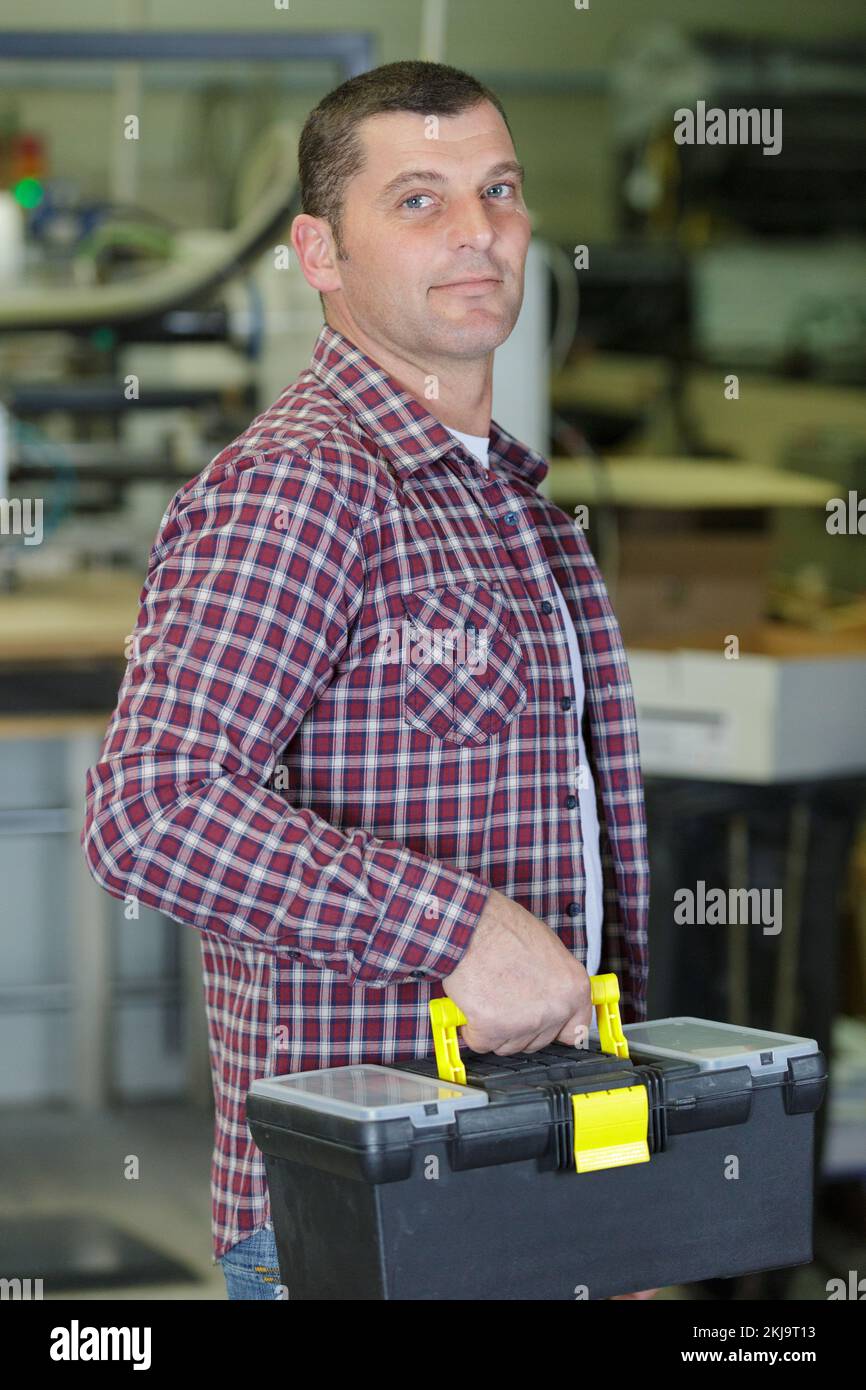 builder carrying toolbox in a workshop Stock Photo - Alamy