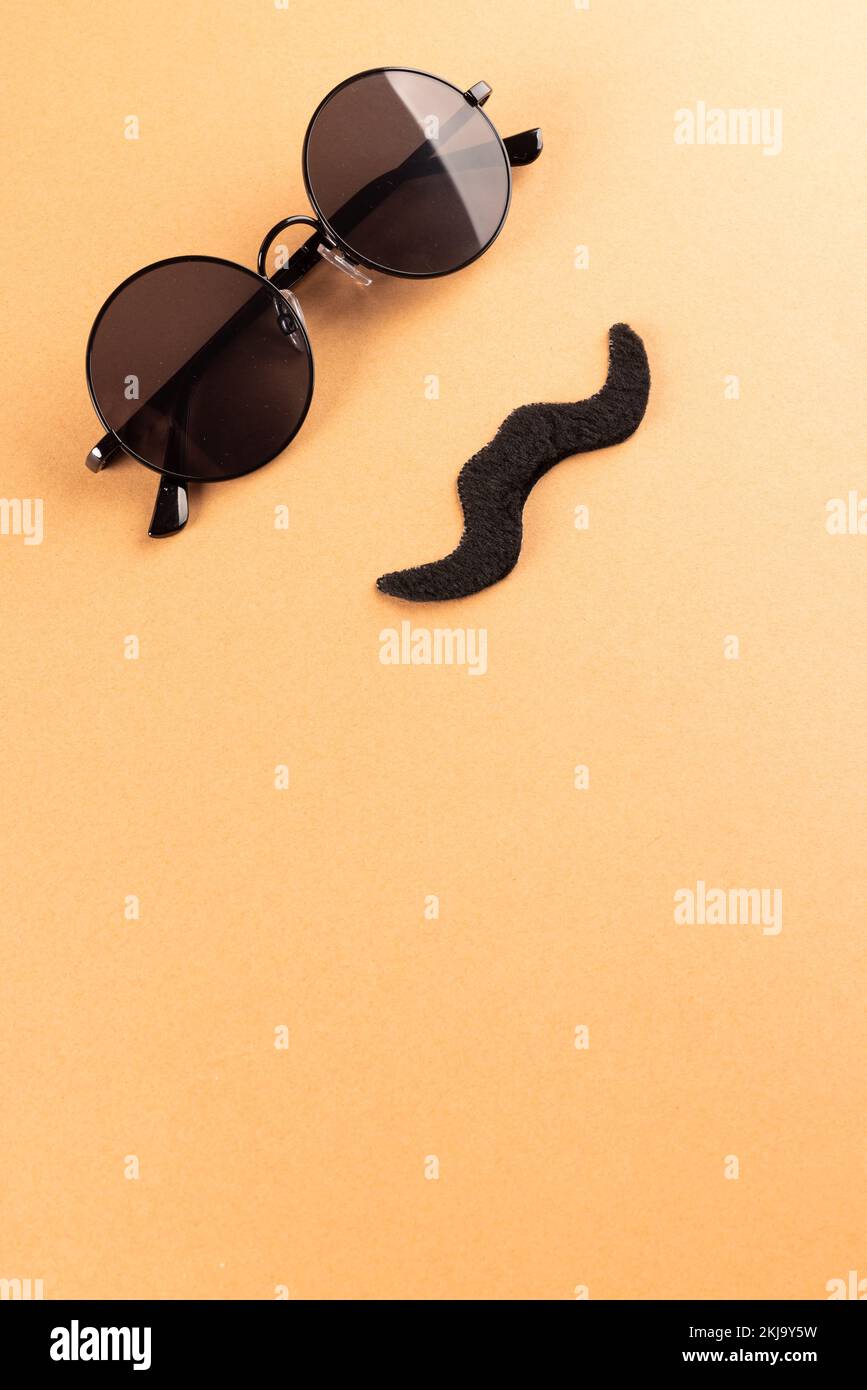 Composition of fake moustache and glasses on orange background with ...