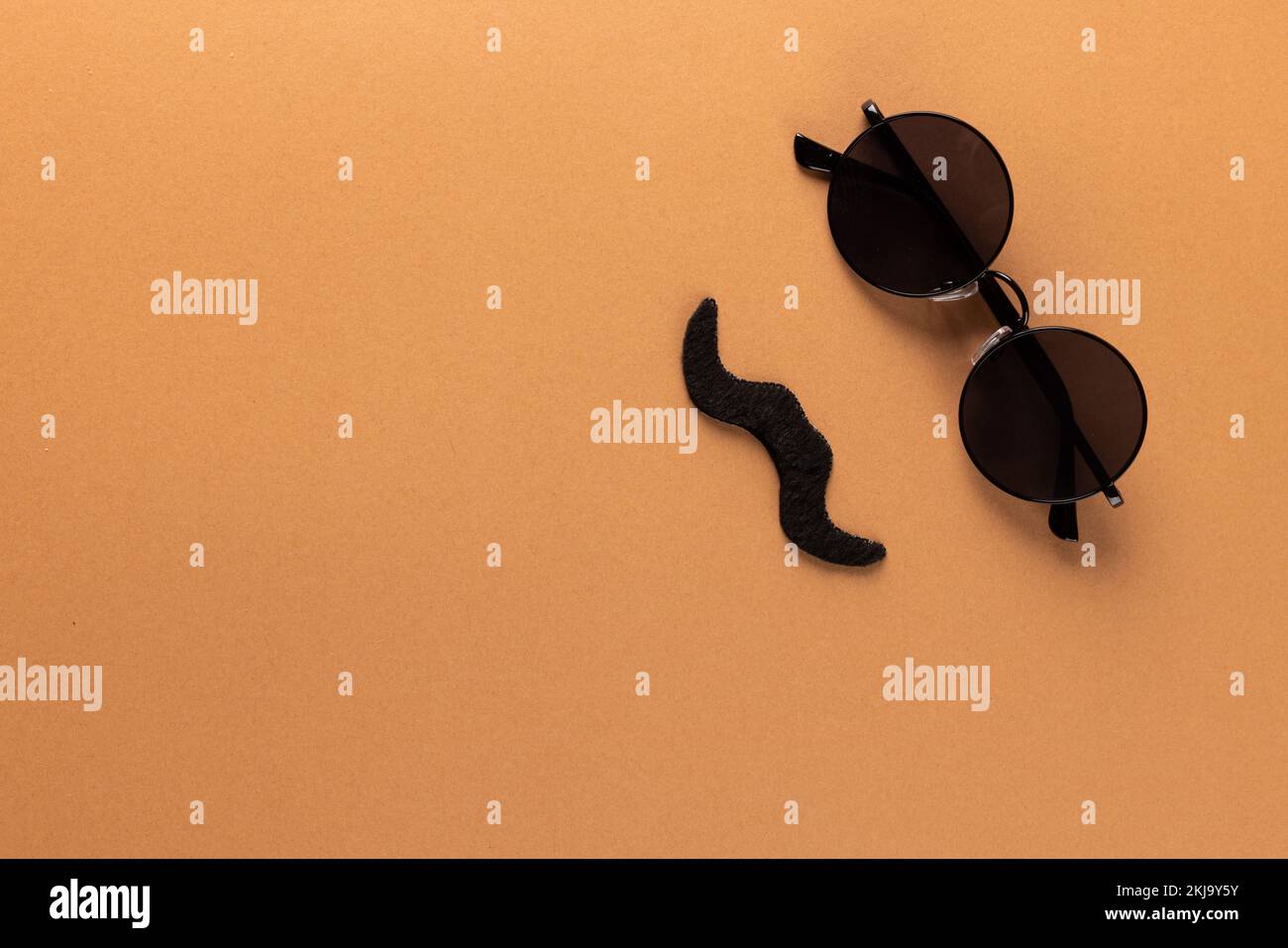 Composition of fake moustache and glasses on orange background with ...