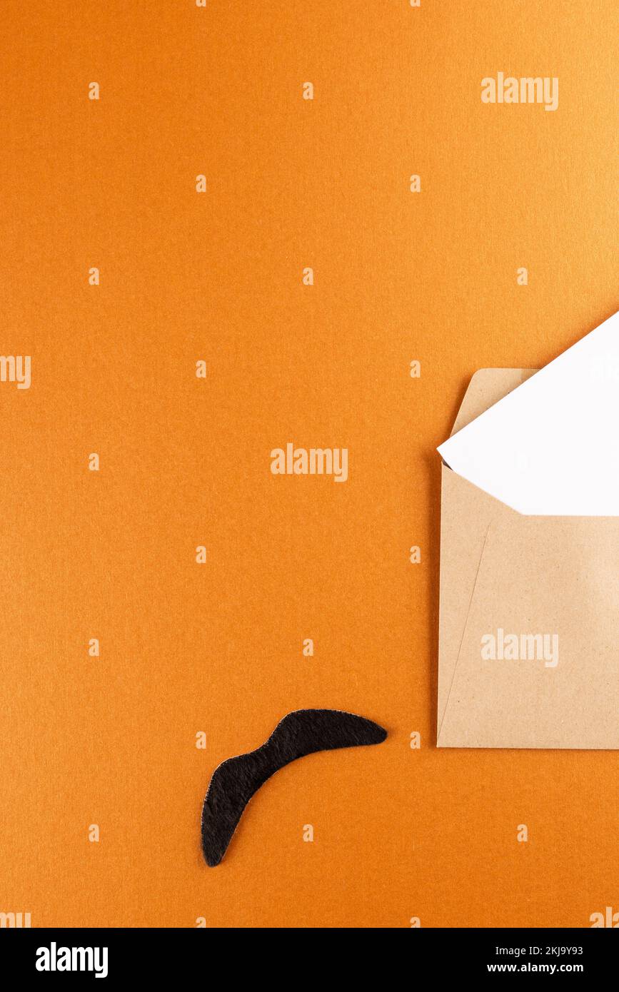 Composition of fake moustache and envelope on orange background with ...