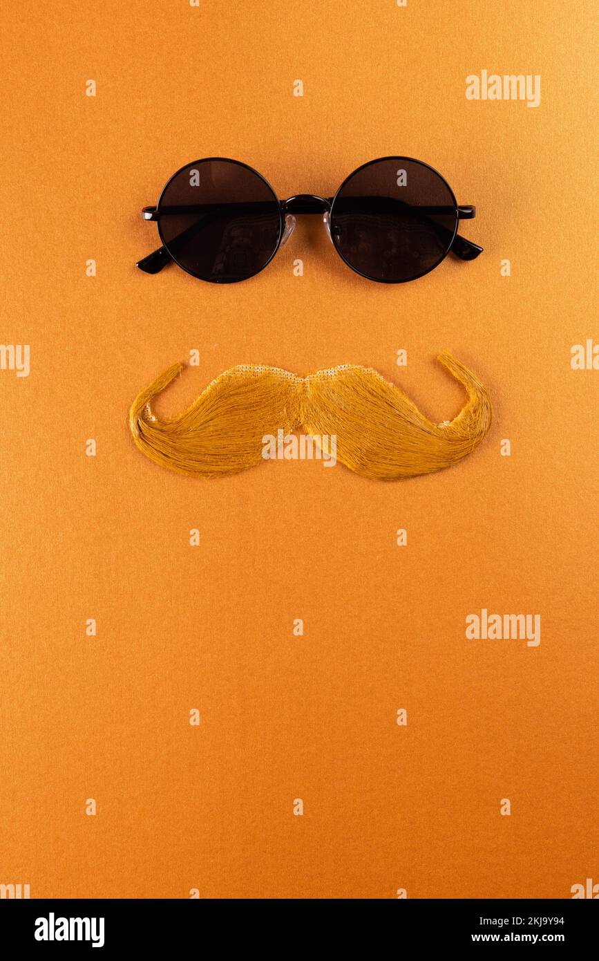 Composition of fake moustache and glasses on orange background with ...