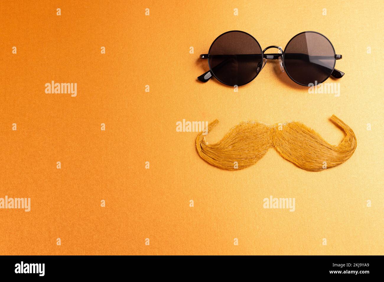 Composition of fake moustache and glasses on orange background with ...