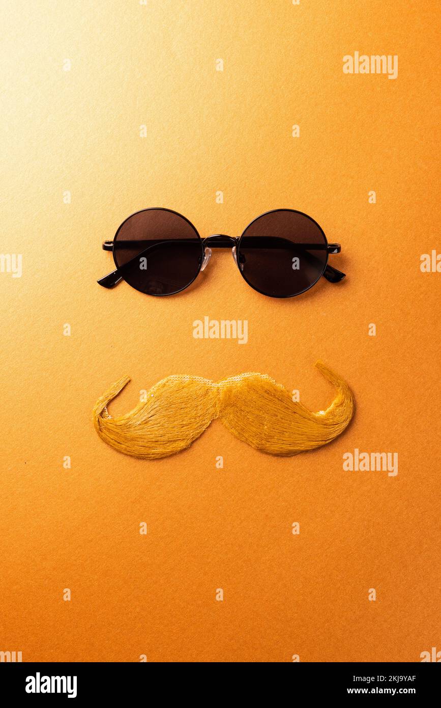 Composition of fake moustache and glasses on orange background with ...