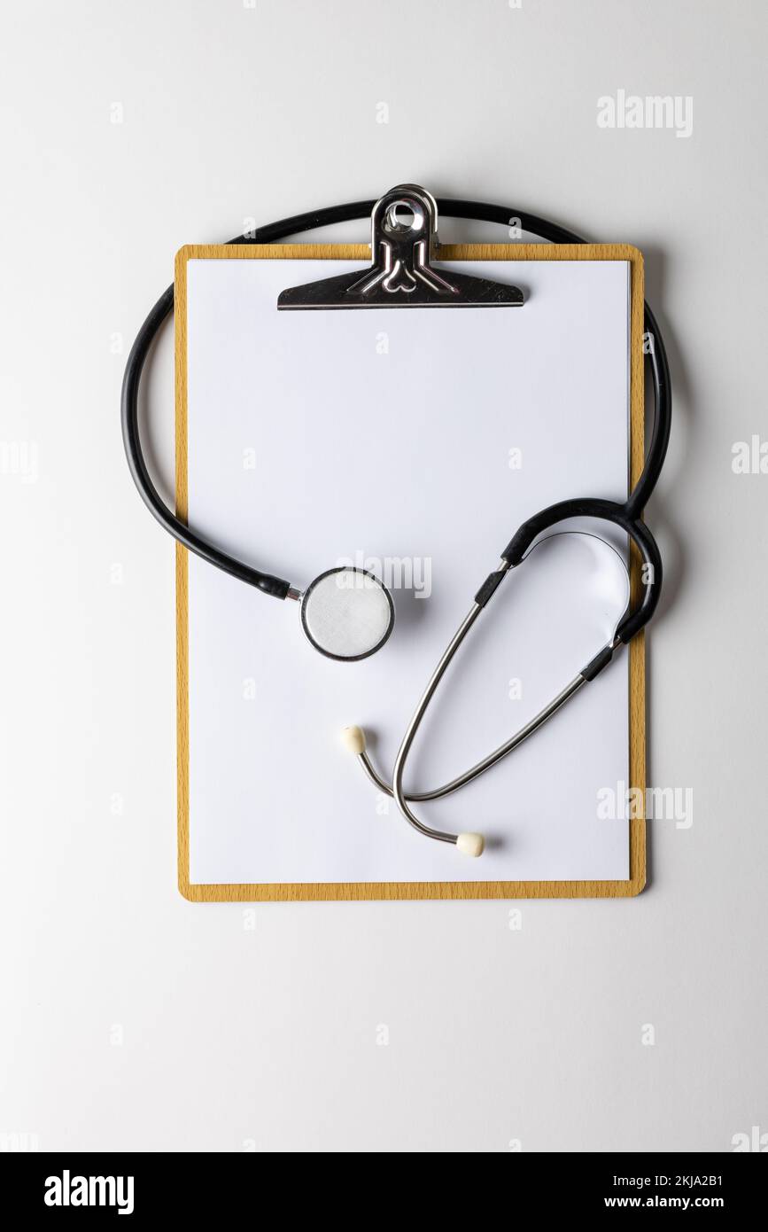 Vertical composition of stethoscope with clipboard on white background ...
