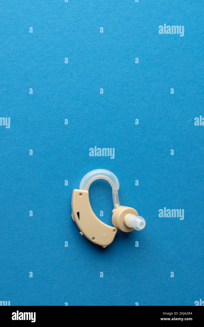 Vertical composition of hearing aid on blue background with copy space ...