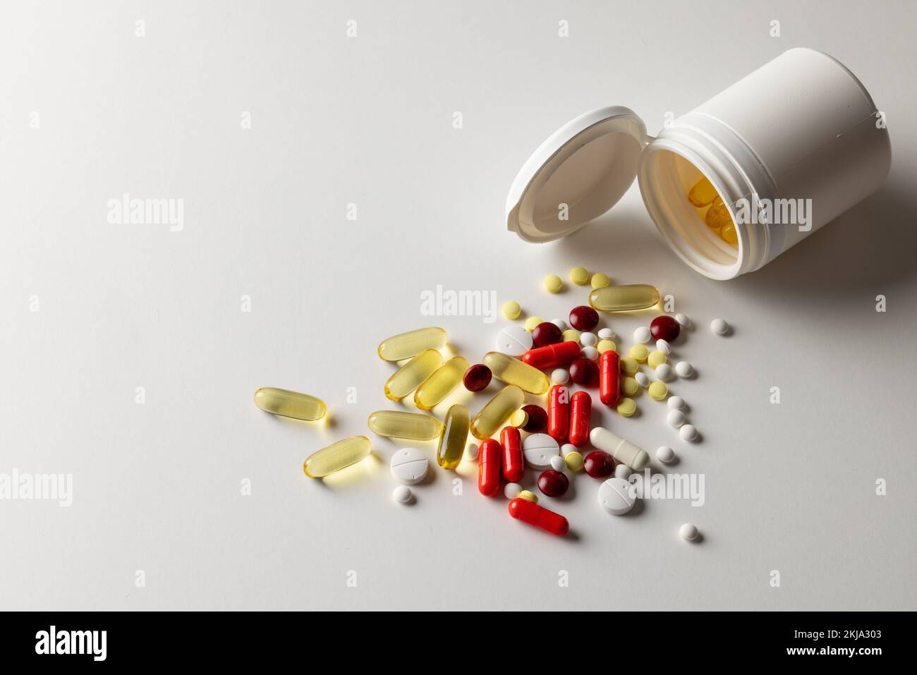 Composition of pill box spilling a variety of pills and capsules on ...