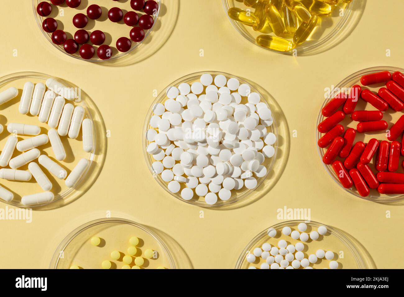 Composition of a variety of pills in glass dishes on yellow background ...