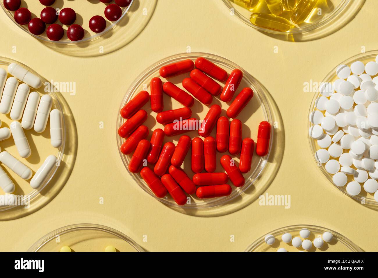 Composition of a variety of pills in glass dishes on yellow background ...