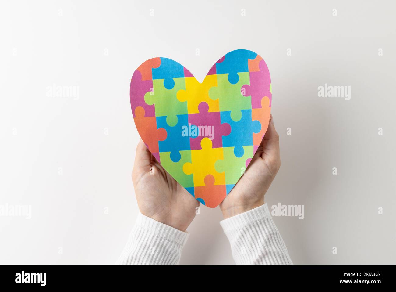 Composition of hands holding jigsaw puzzle heart on white background ...