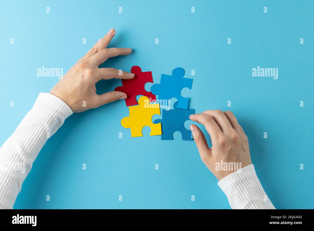 Composition of hands putting jigsaw puzzle pieces together on blue ...