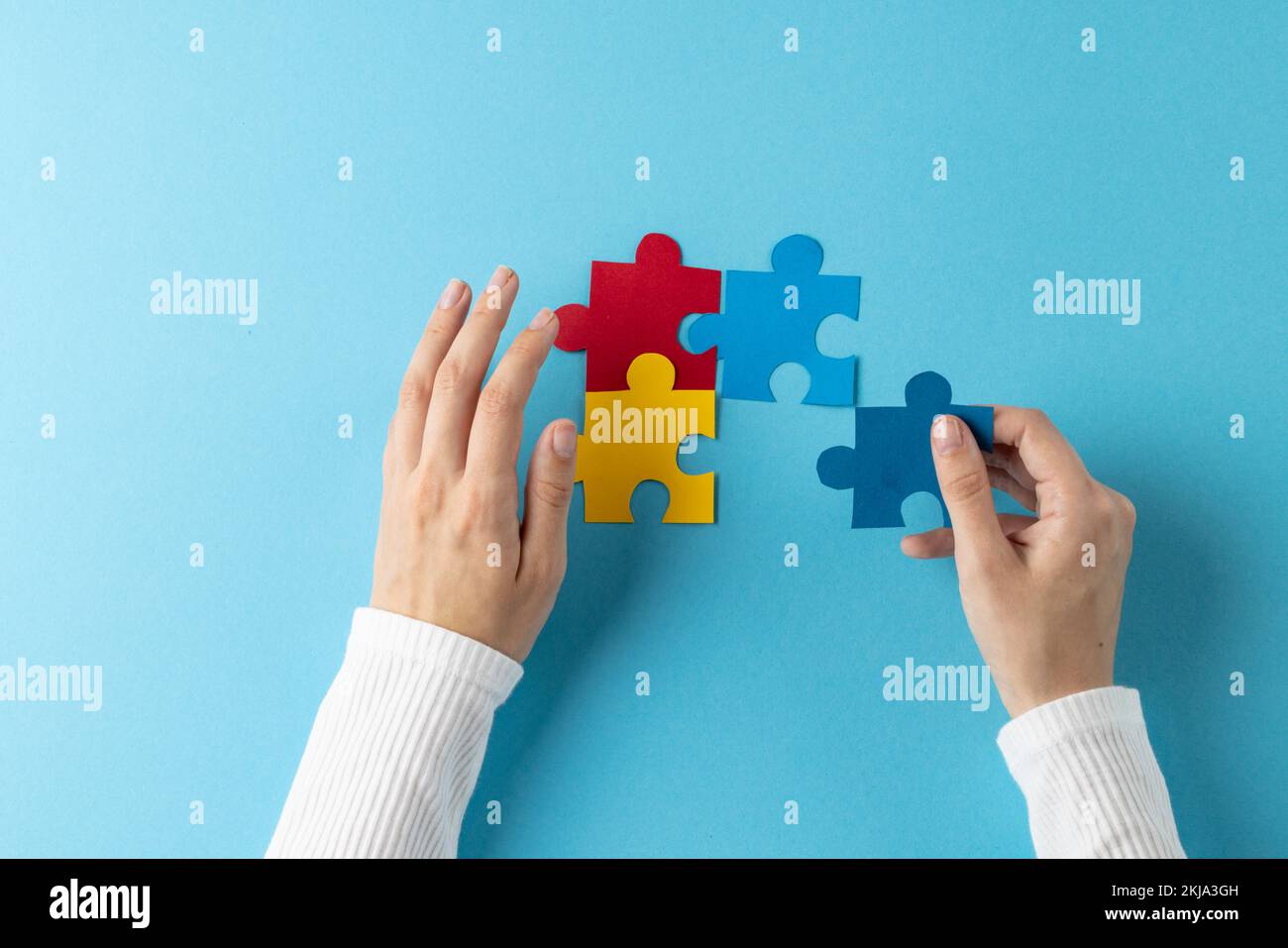 Composition of hands putting jigsaw puzzle pieces together on blue ...