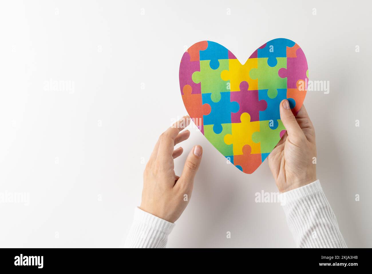 Composition of hands holding jigsaw puzzle heart on white background ...