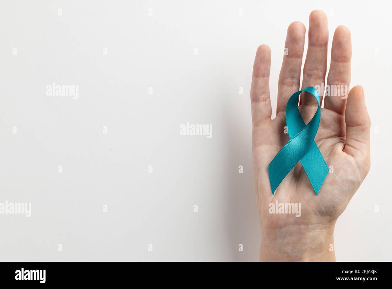Composition of hand holding blue ovarian cancer awareness ribbon on ...