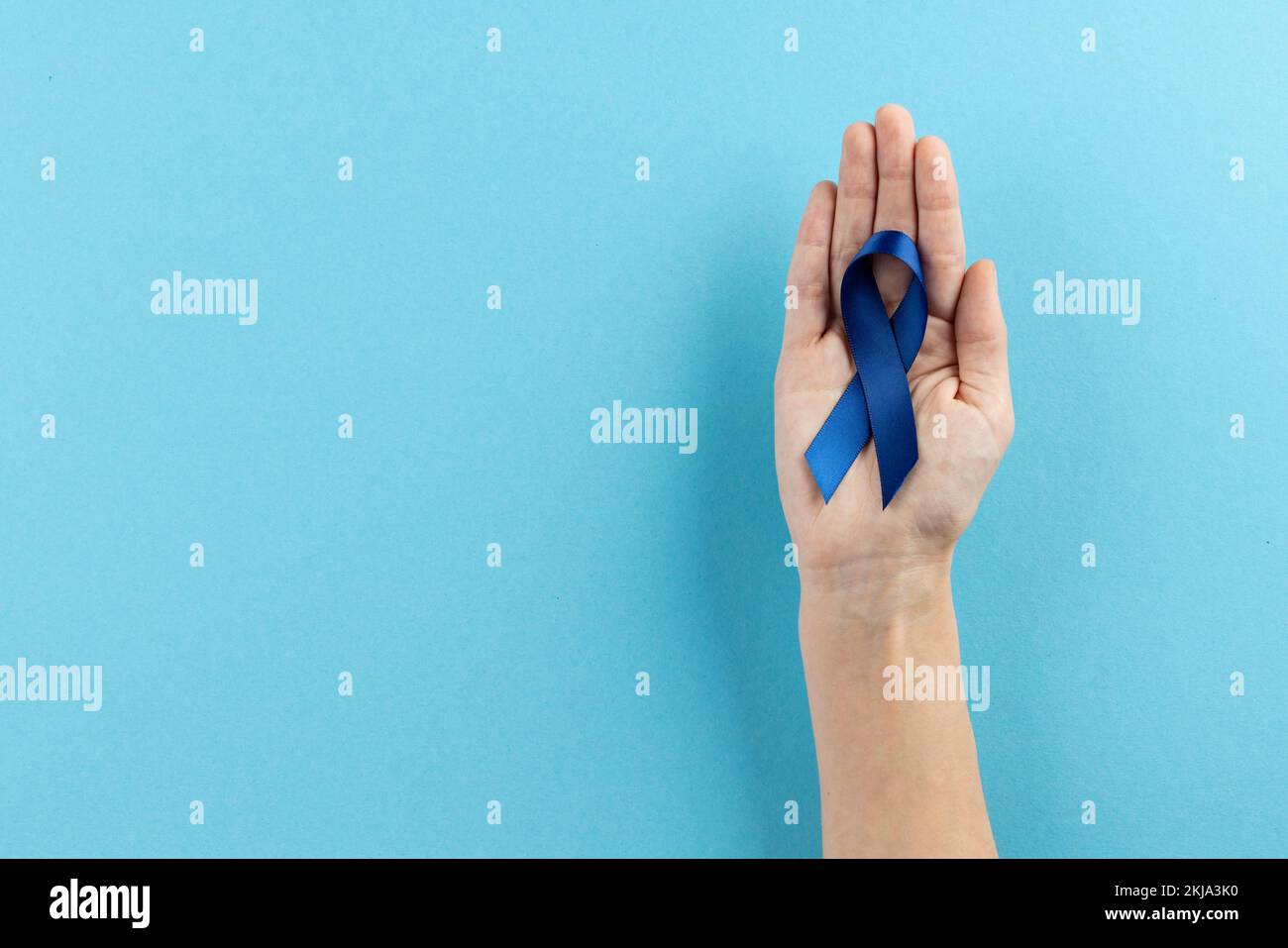 Hand holding blue ribbon on blue background with copy space Stock Photo ...