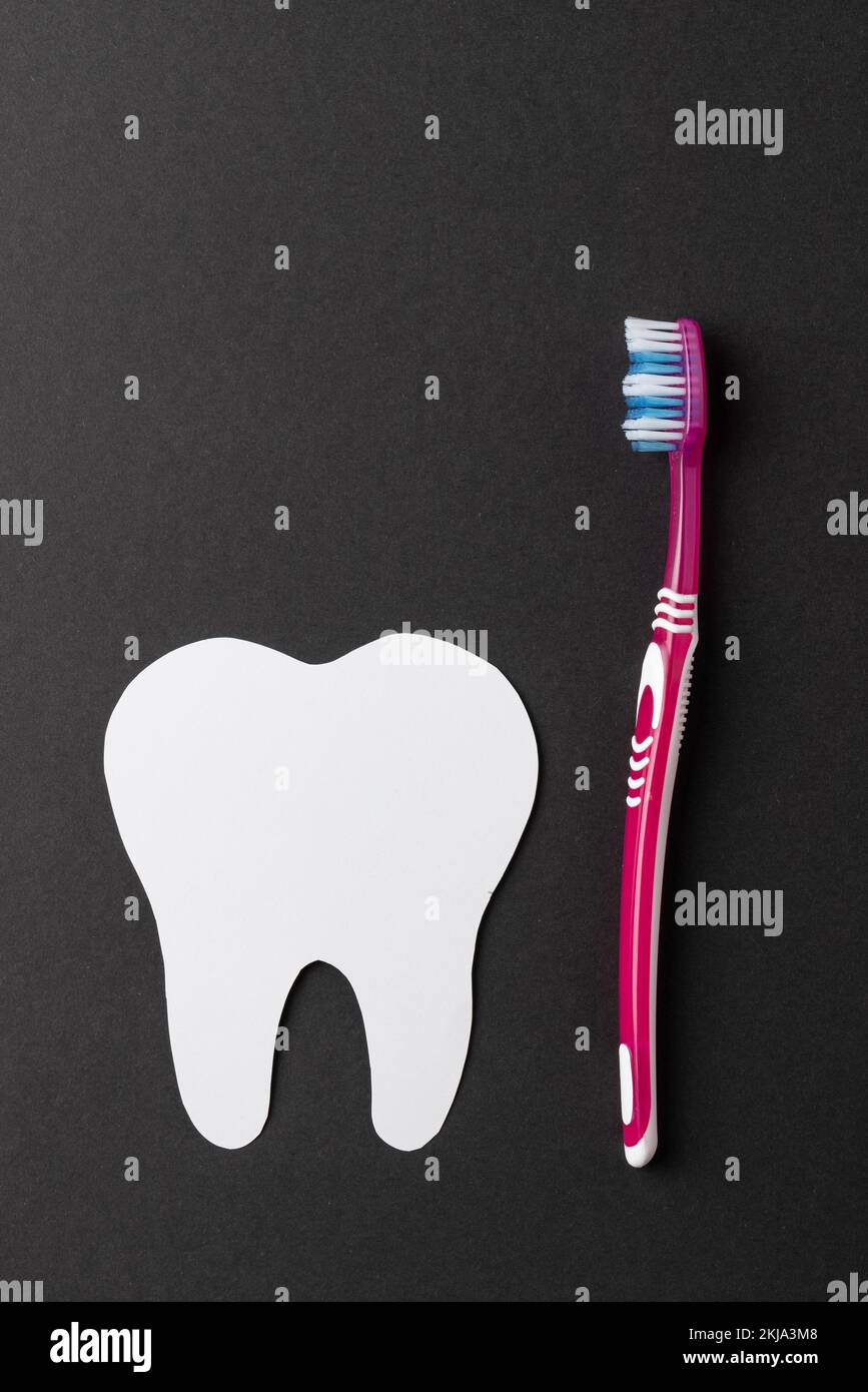 Vertical composition of white tooth and toothbrush on black background ...
