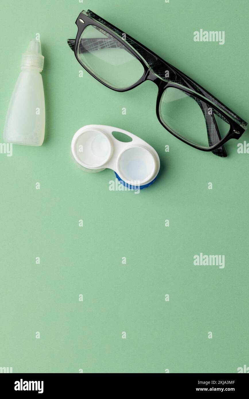 Vertical of glasses with contact lenses case and solution on green ...