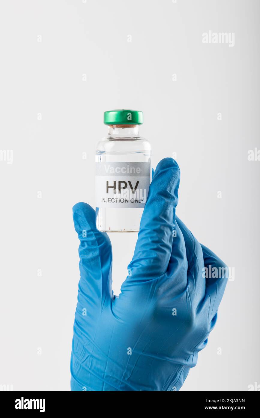 Vertical of doctor's gloved hand holding hpv vaccine vial on white ...