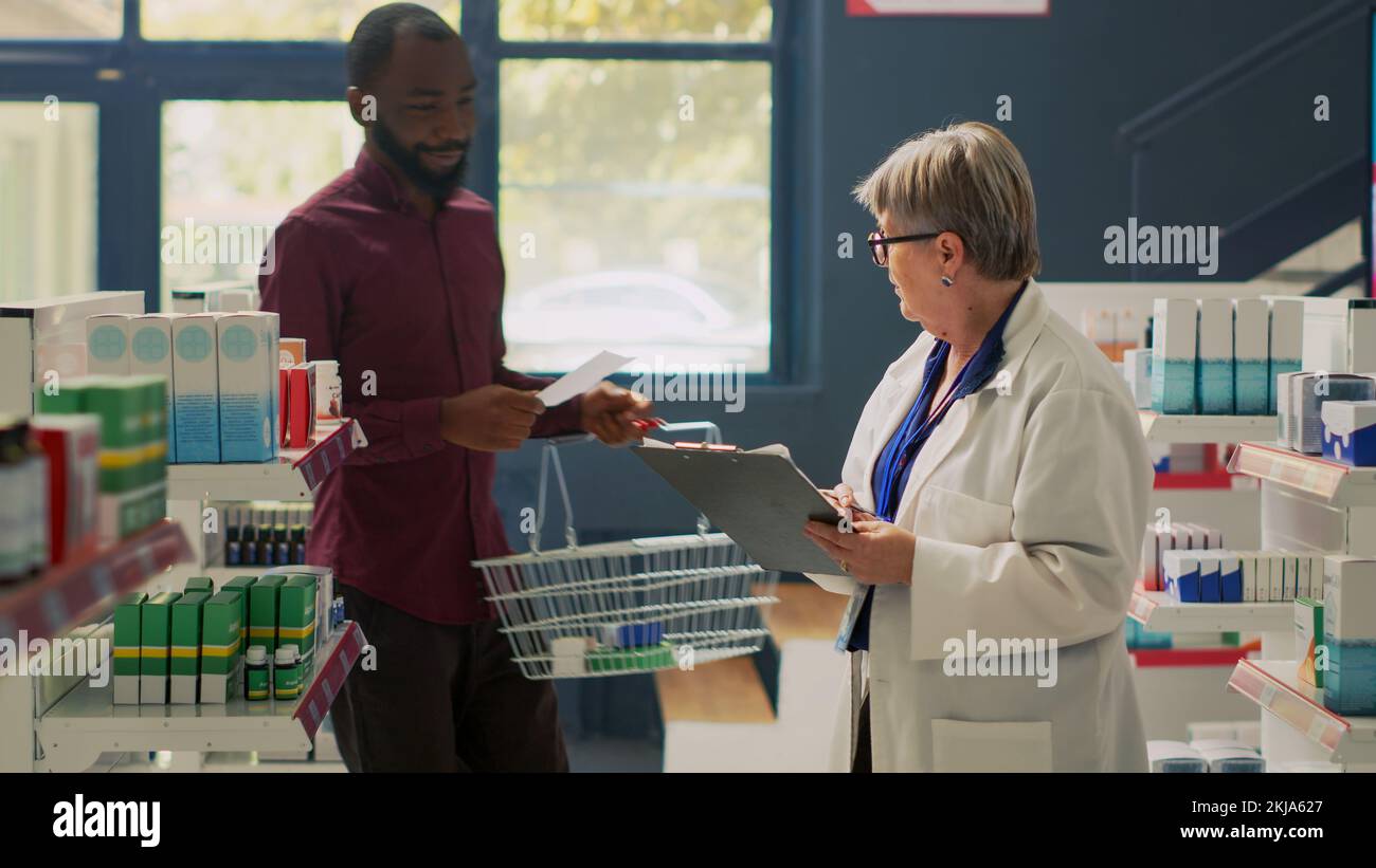 Young adult with prescription paper asking pharmacist about treatment ...