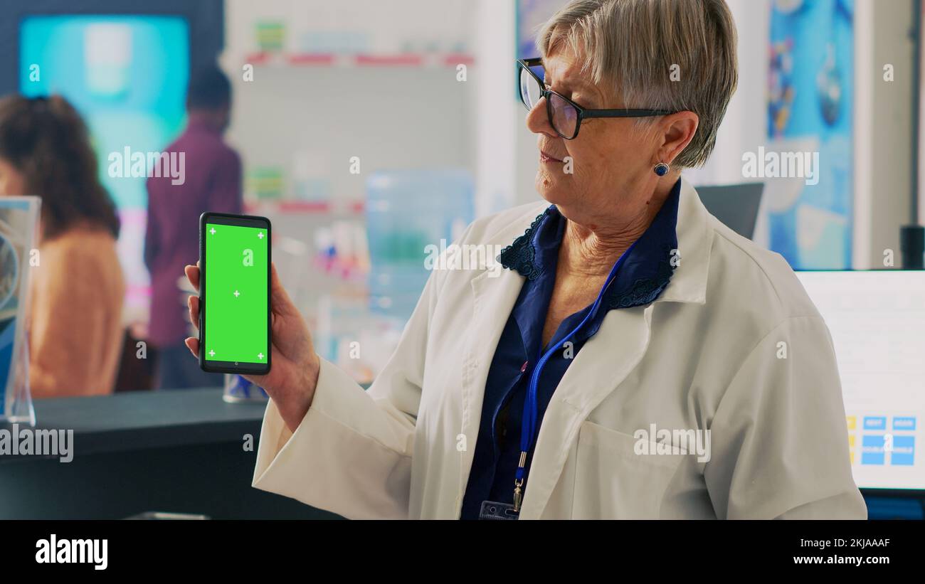 Medical assistant showing smartphone with greenscreen display, holding ...