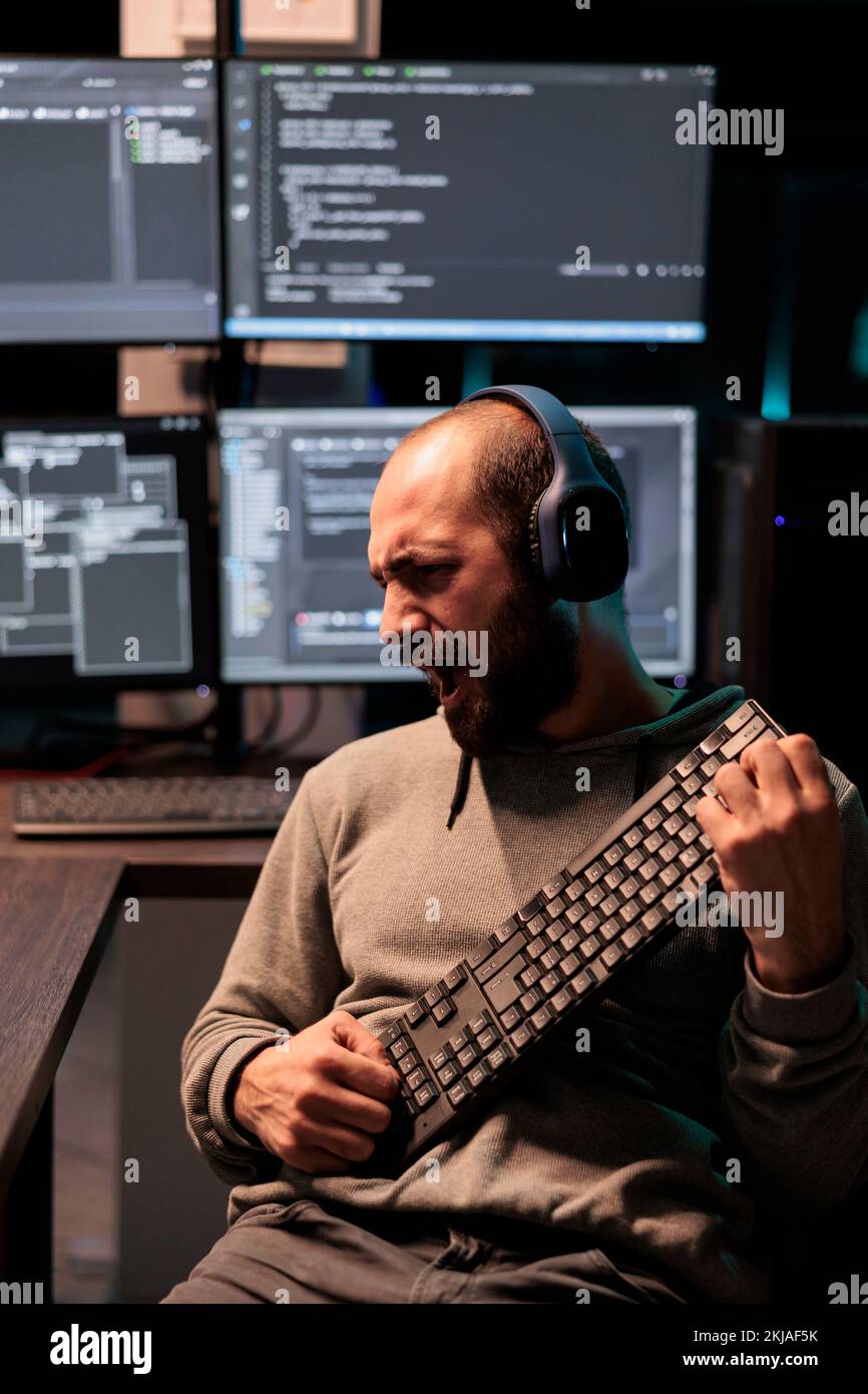 Funky developer singing at air guitar keyboard late at night, working ...