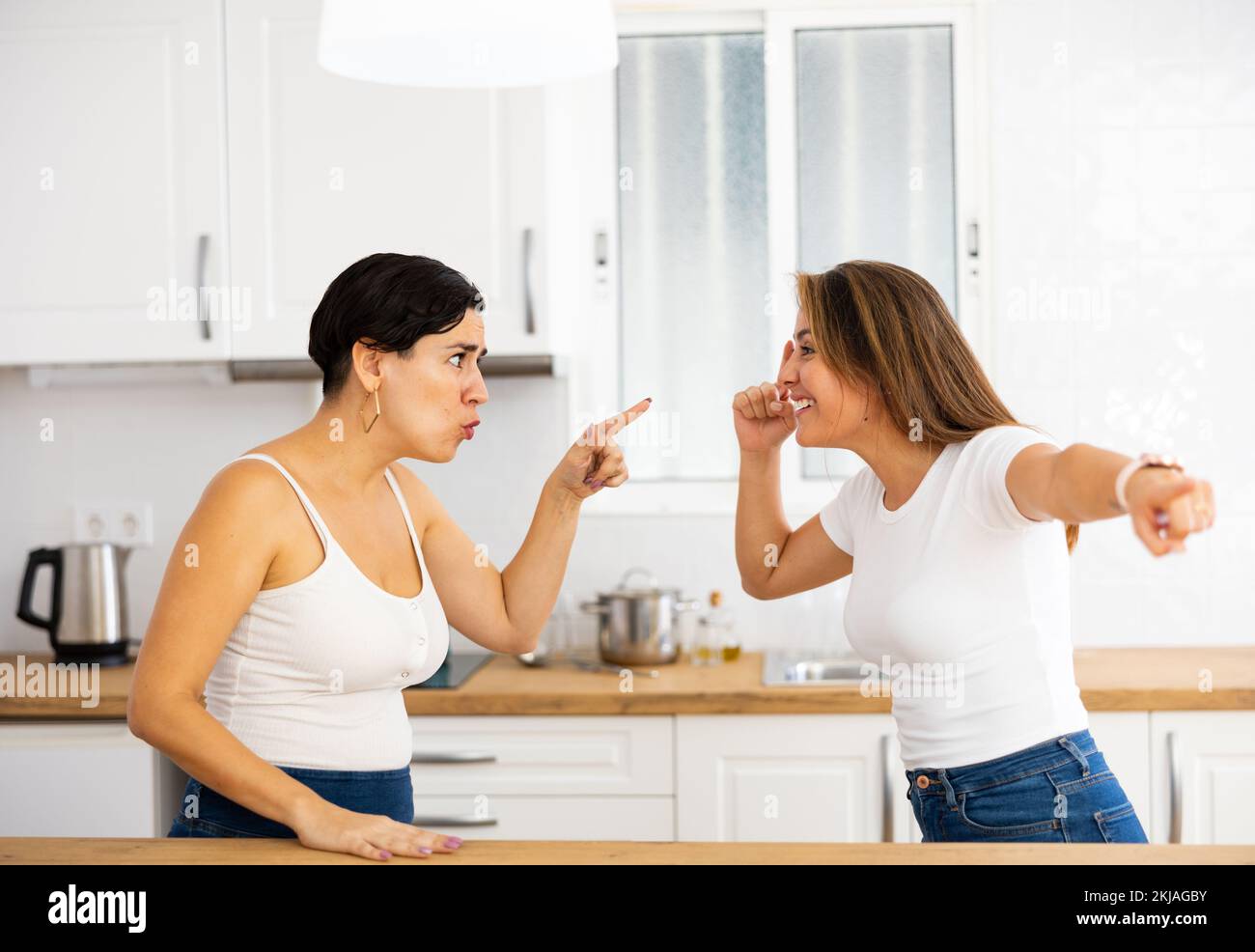 Two young Hispanic women emotionally arguing in kitchen Stock Photo - Alamy