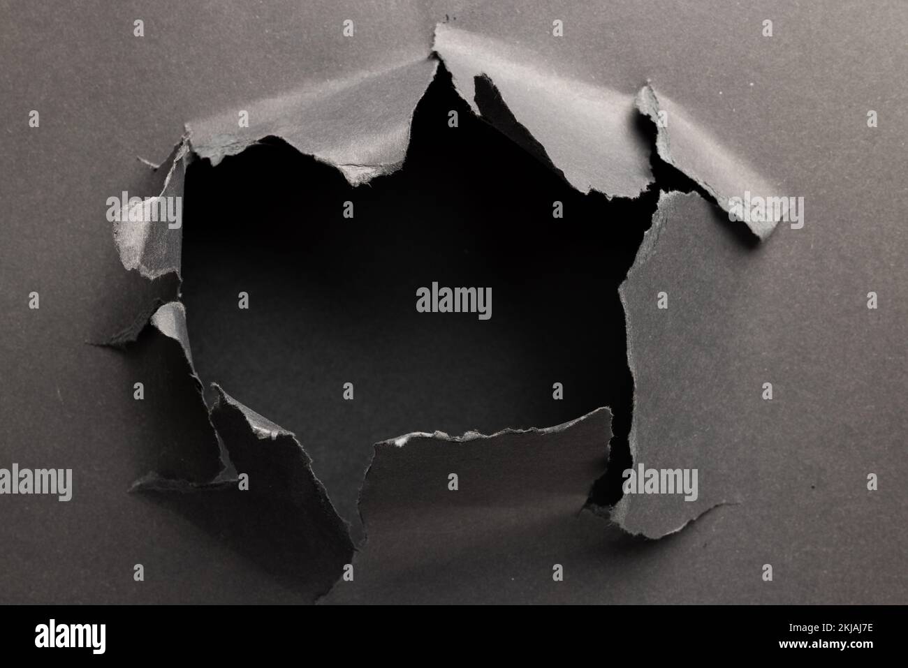 Ripped up piece of black paper with copy space on black background ...