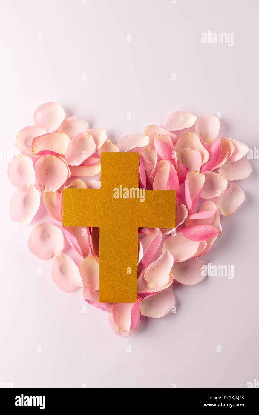 Vertical overhead of yellow christian cross on heart of pink rose ...