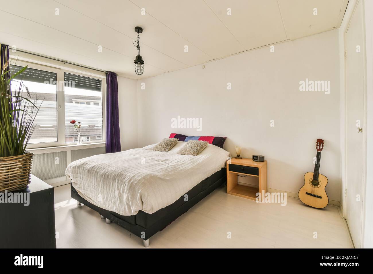 Sunlit bed covered with blanket in light contemporary bedroom with ...