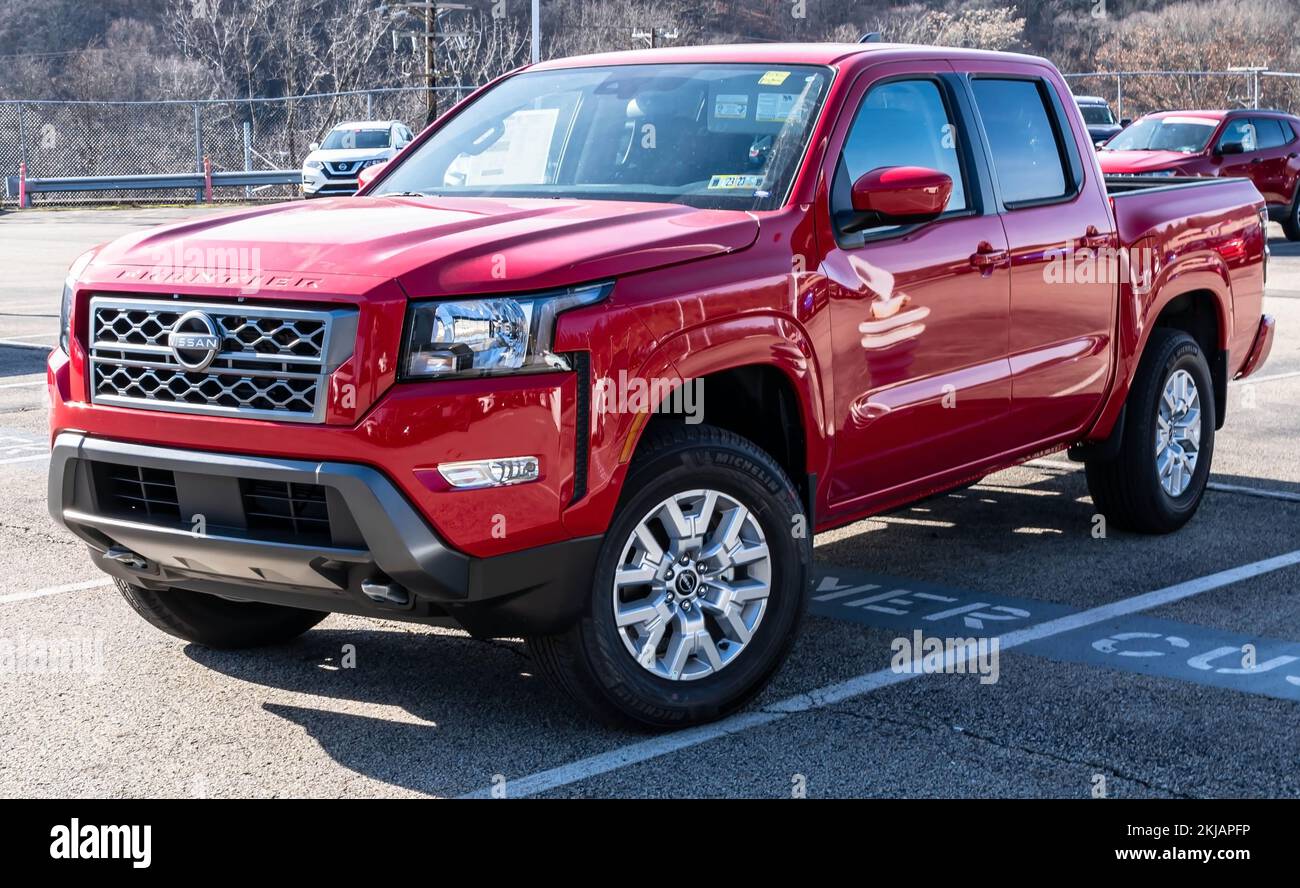 A new, red four door Nissan Frontier pickup truck for sale at a ...