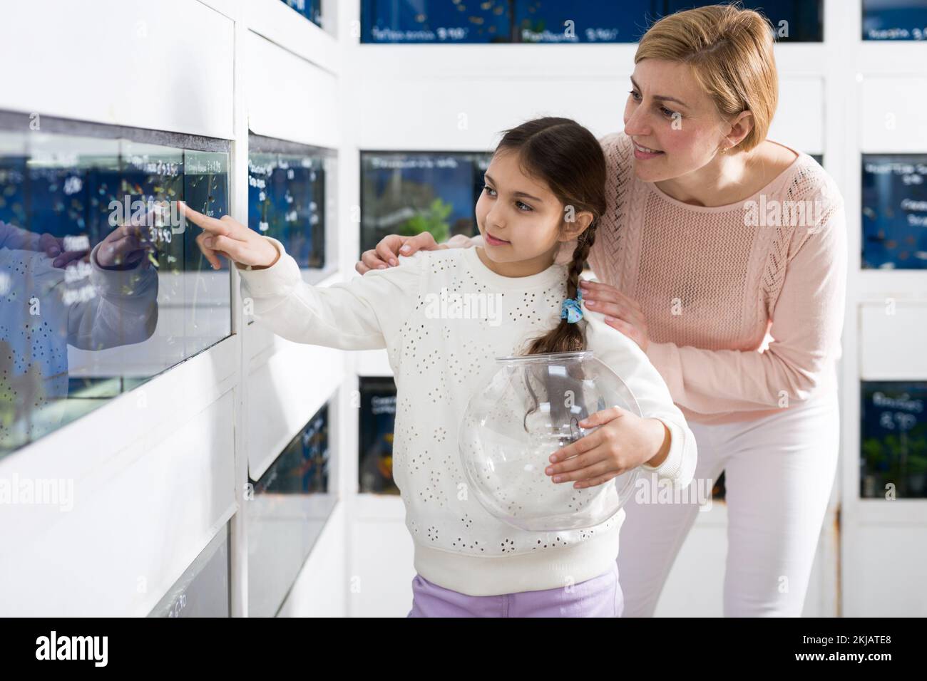 Cute girl with her mother customer buying tropical fish Stock Photo - Alamy