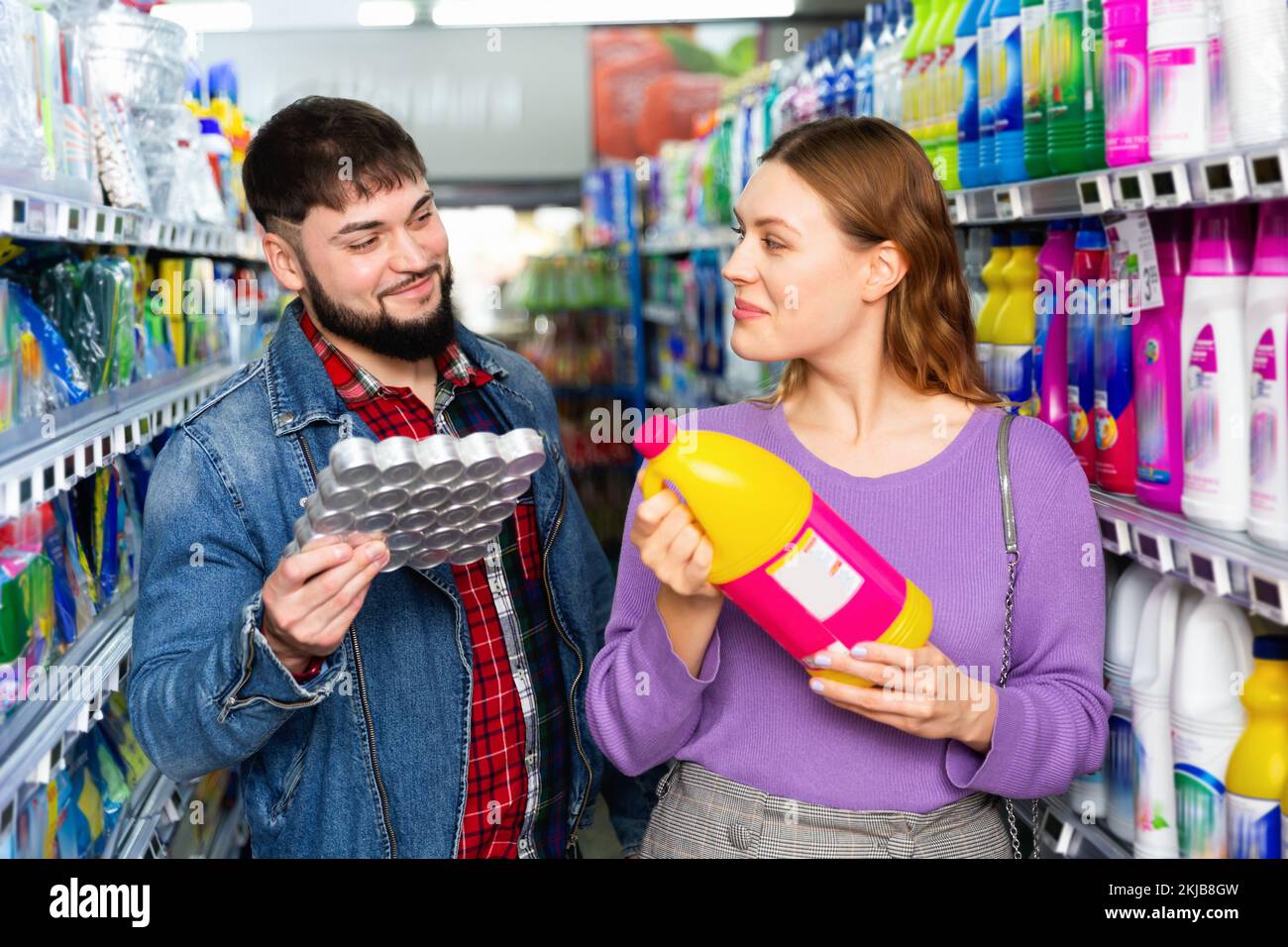Portrait of positive young woman and man choosing liquid laundry ...