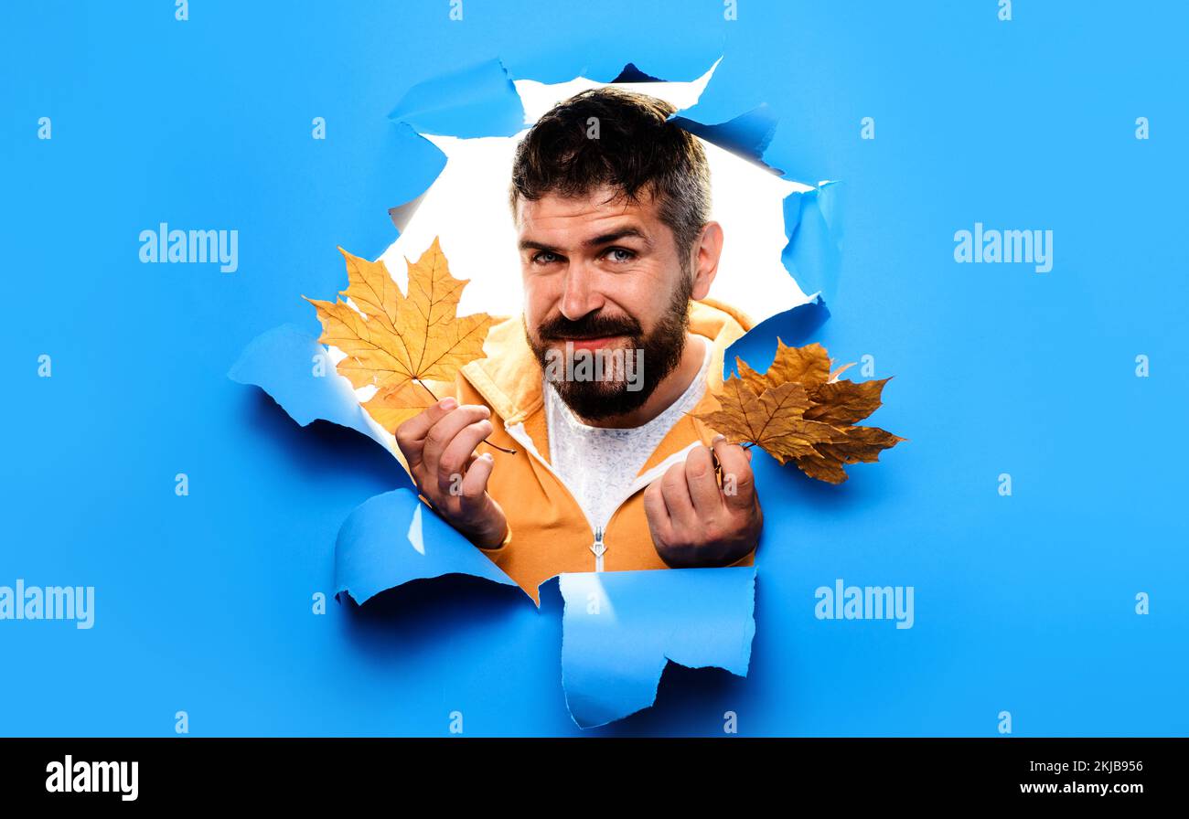 Smiling bearded man looking through paper hole. Autumn clothes ...